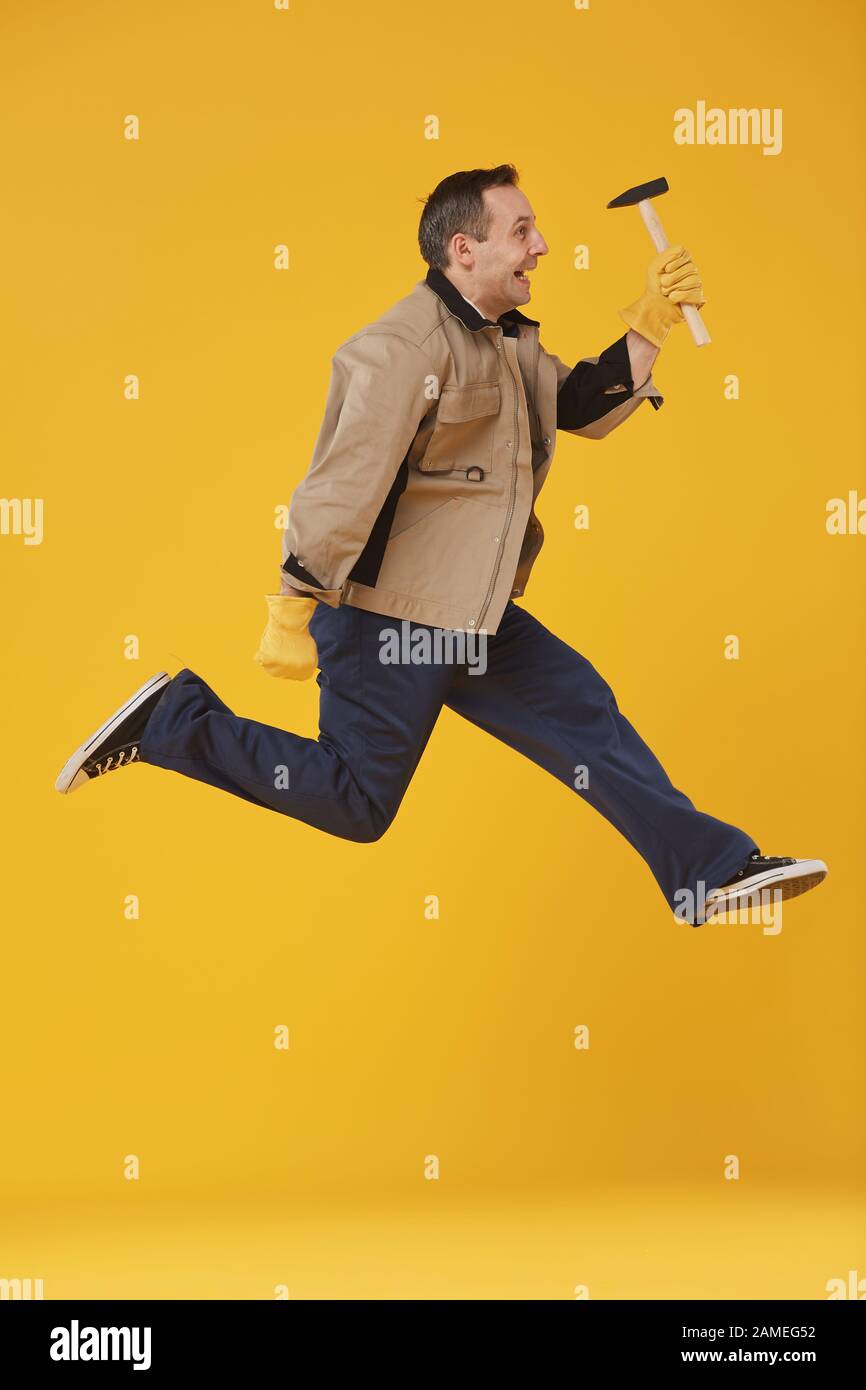 Side view full length of joyful mature worker jumping high holding ...