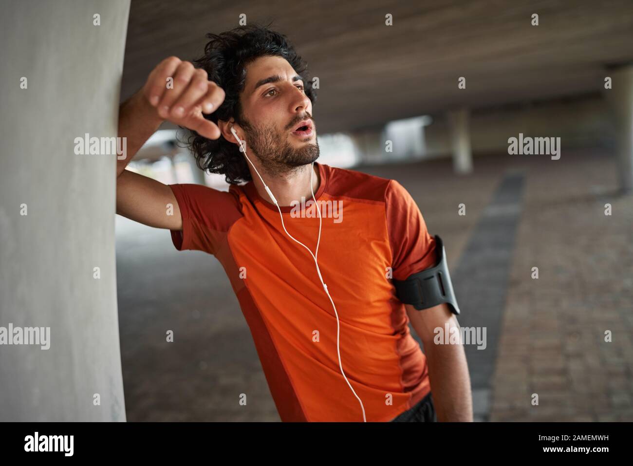 Portrait of a fitness athlete man in earphone breathing heavily after ...