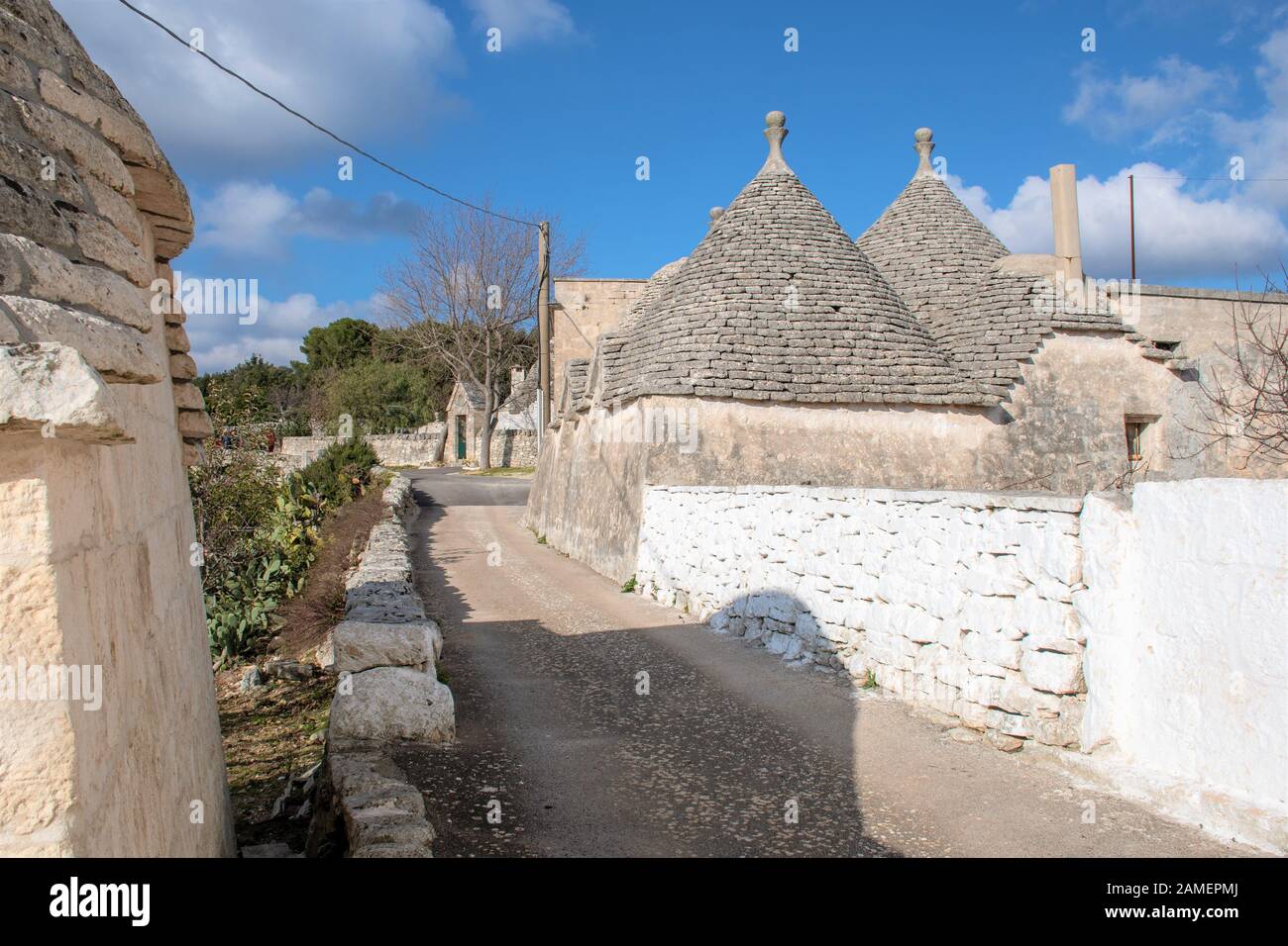 Group of beautiful Trulli, traditional old houses and old stone wall in ...