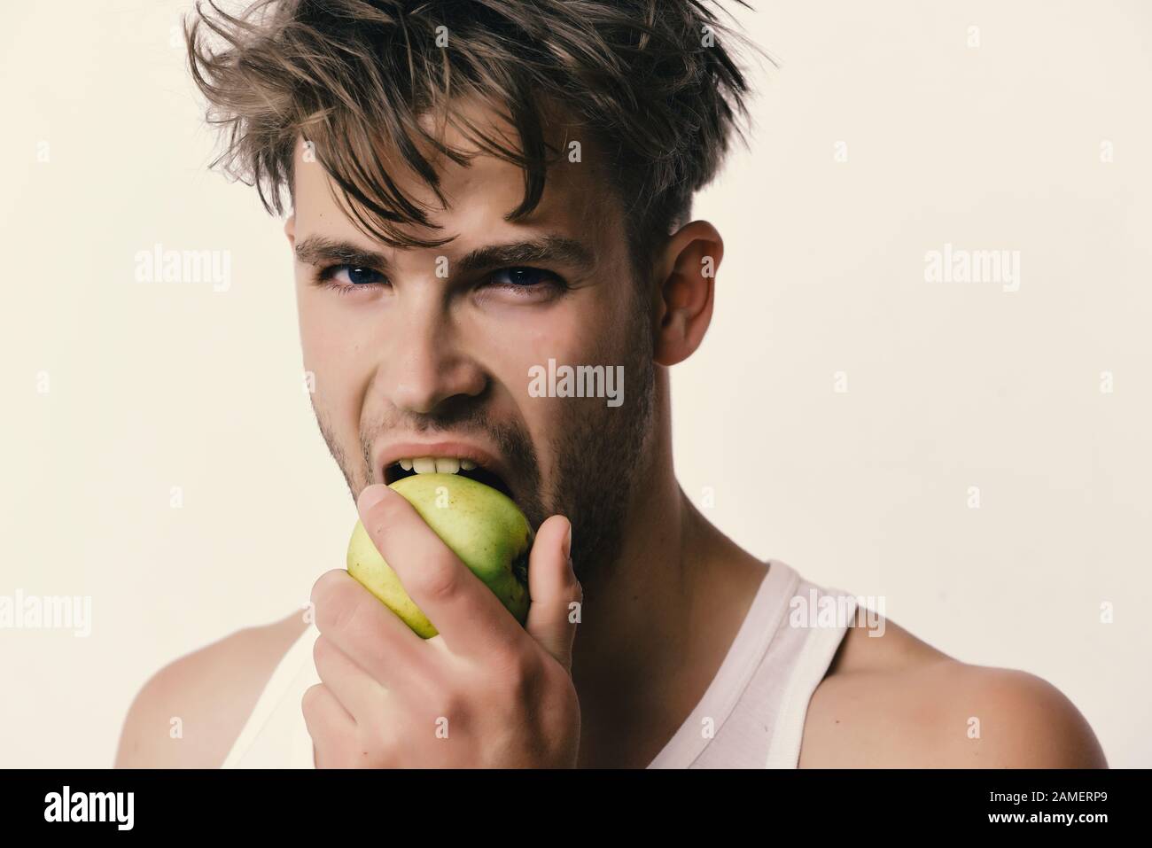 Healthy nutrition concept. Athlete with messy hair eats fresh fruit ...