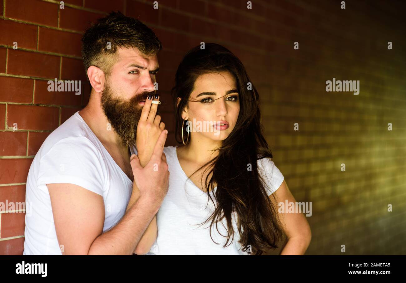 Couple in love hugs while smoking cigarette brick wall background ...