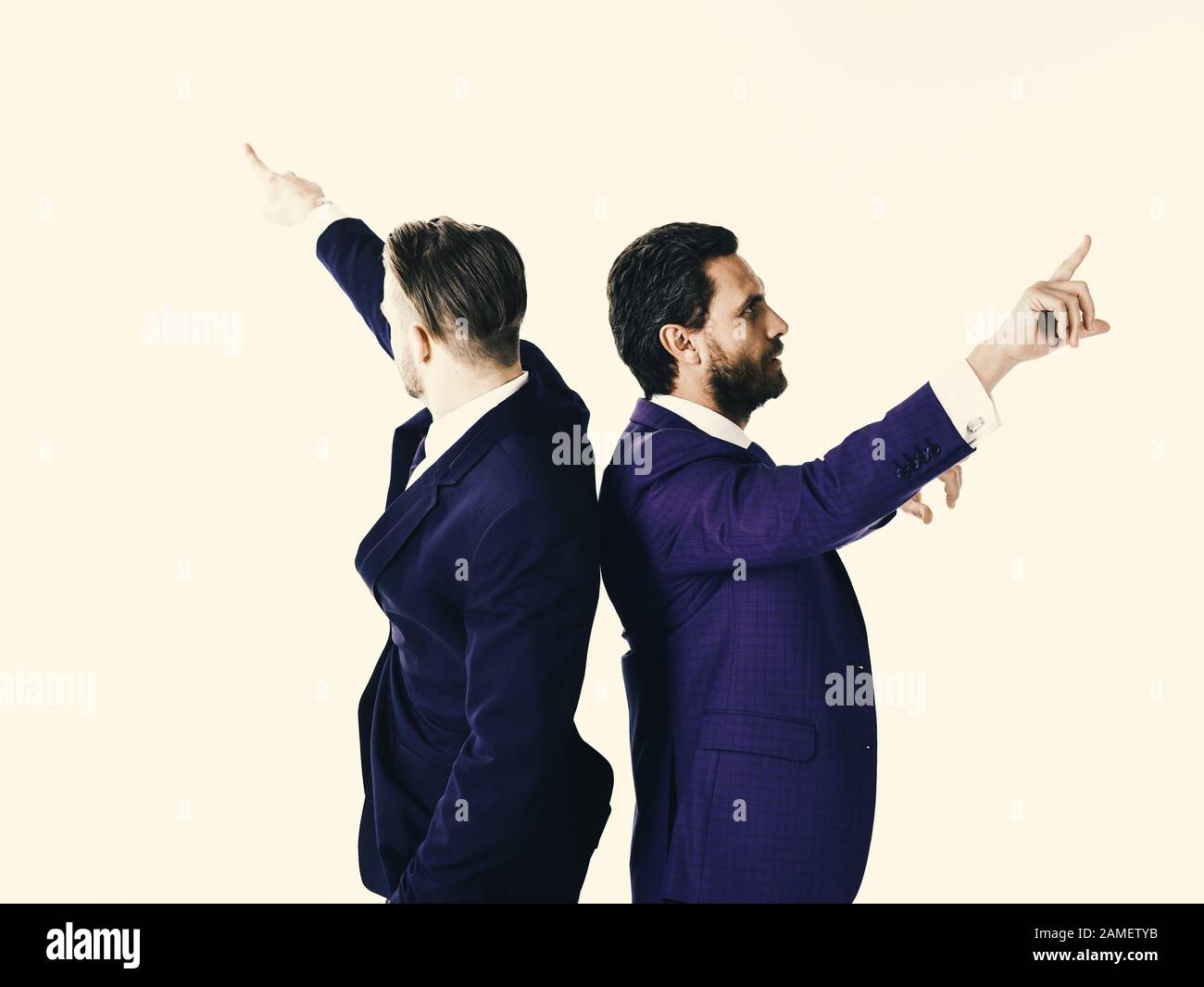 Young businessmen pointing in two different directions at same time ...