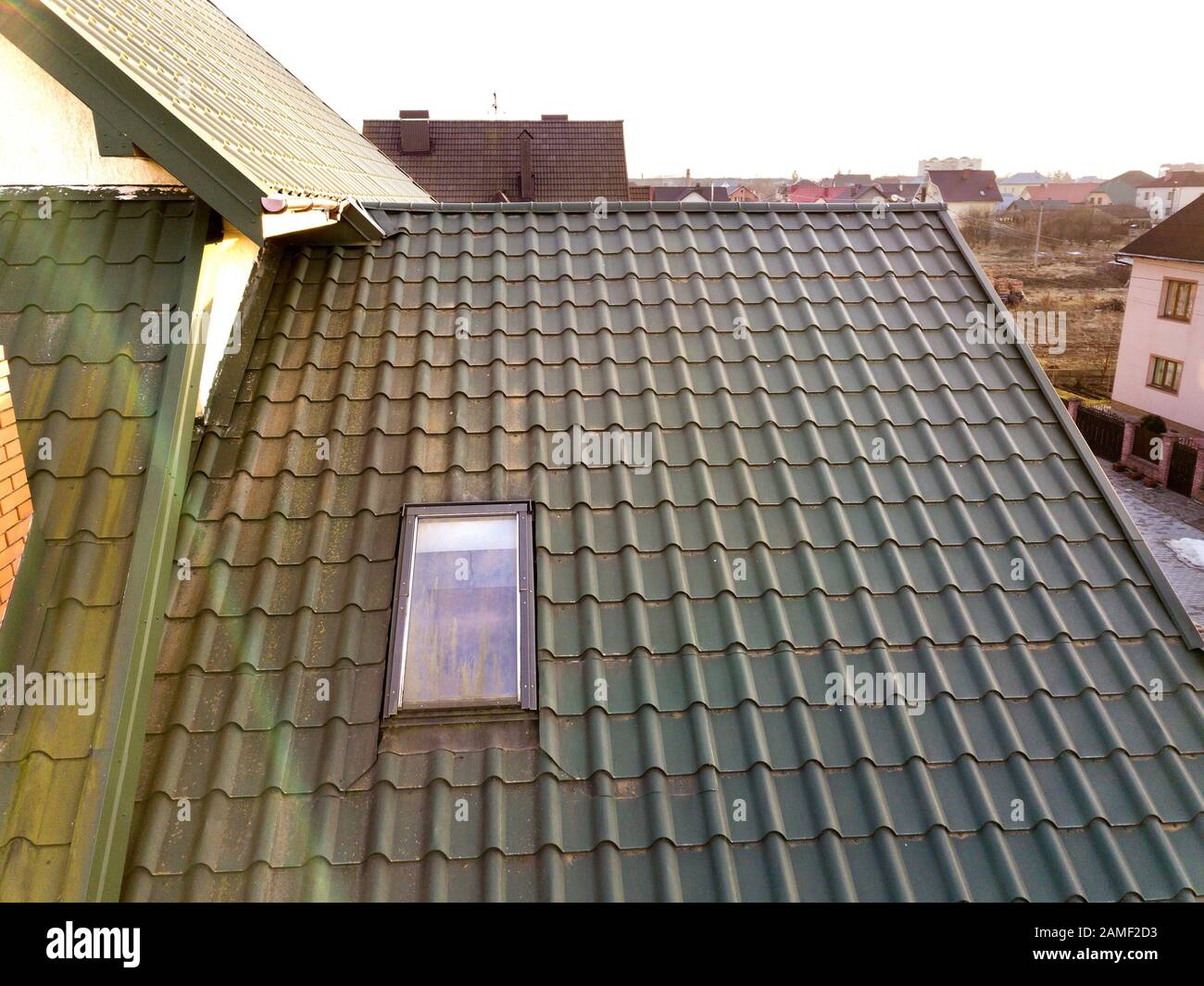 Close-up of new attic plastic window installed in shingled house roof ...