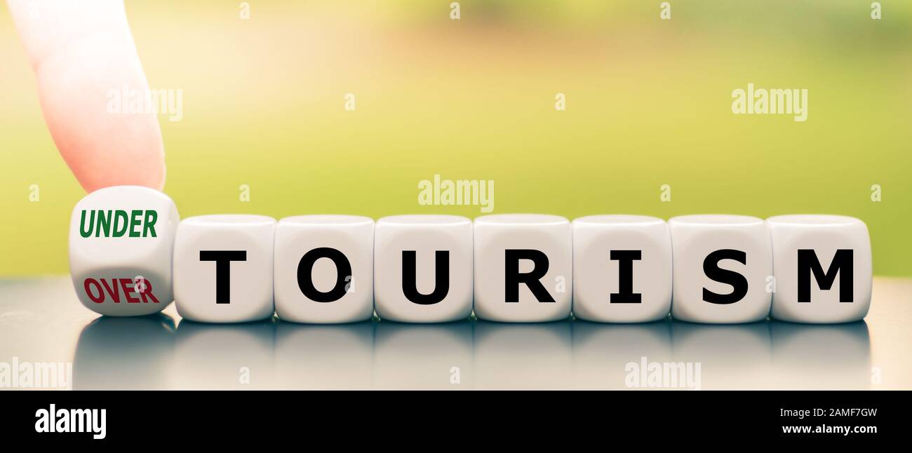 Hand turns a dice and changes the expression "over tourism" to "under ...