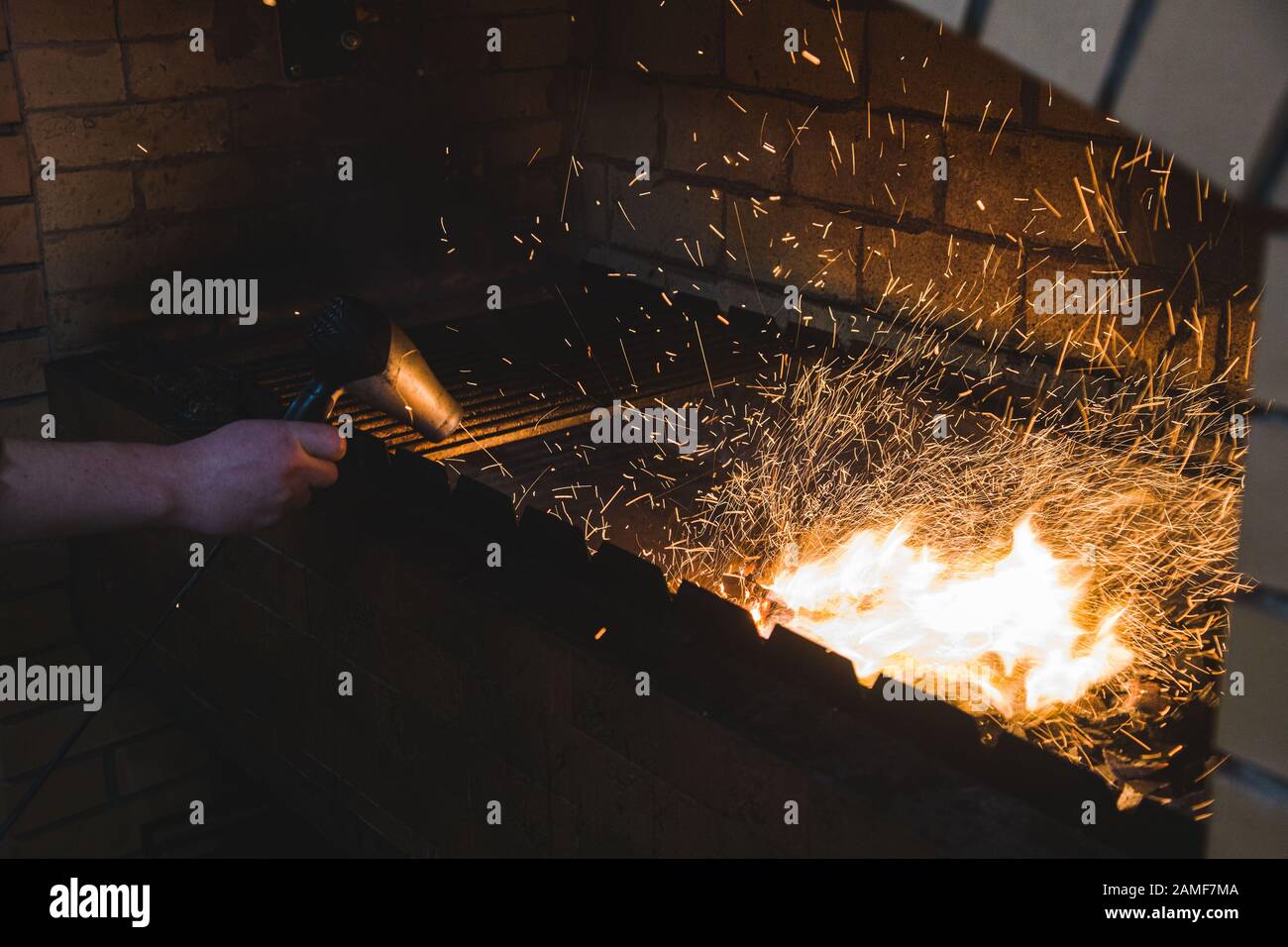 Cooking on fire in a restaurant. Cook inflates the coals. flying sparks ...