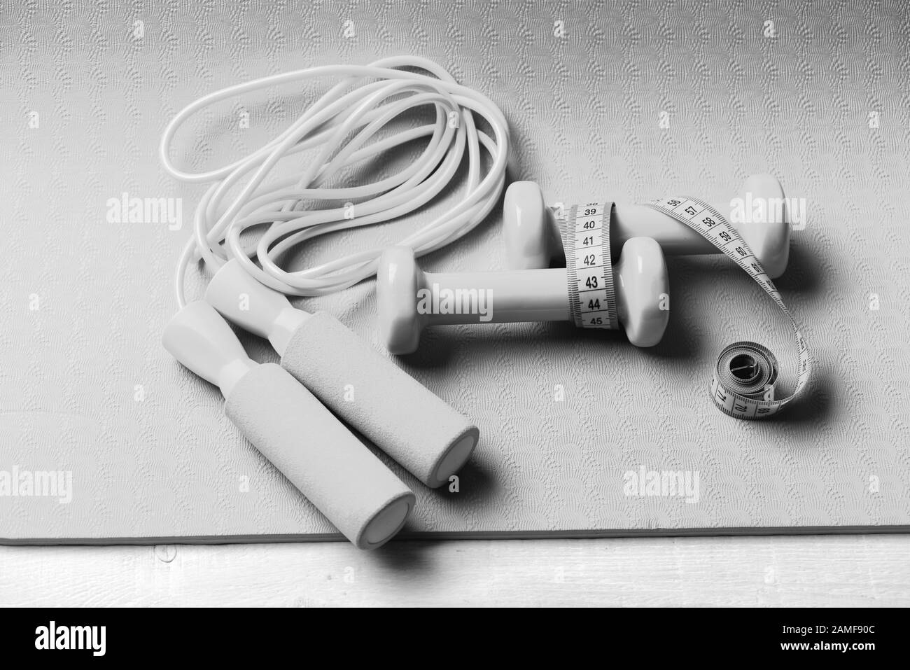 Dumbbells and jump rope in cyan blue color on purple background ...