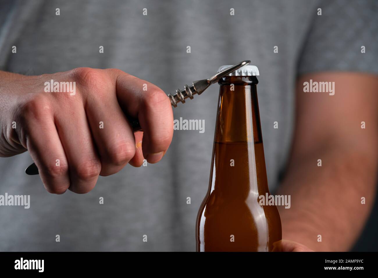 Men opening cold bottle of beer with cap on black background. Hands ...