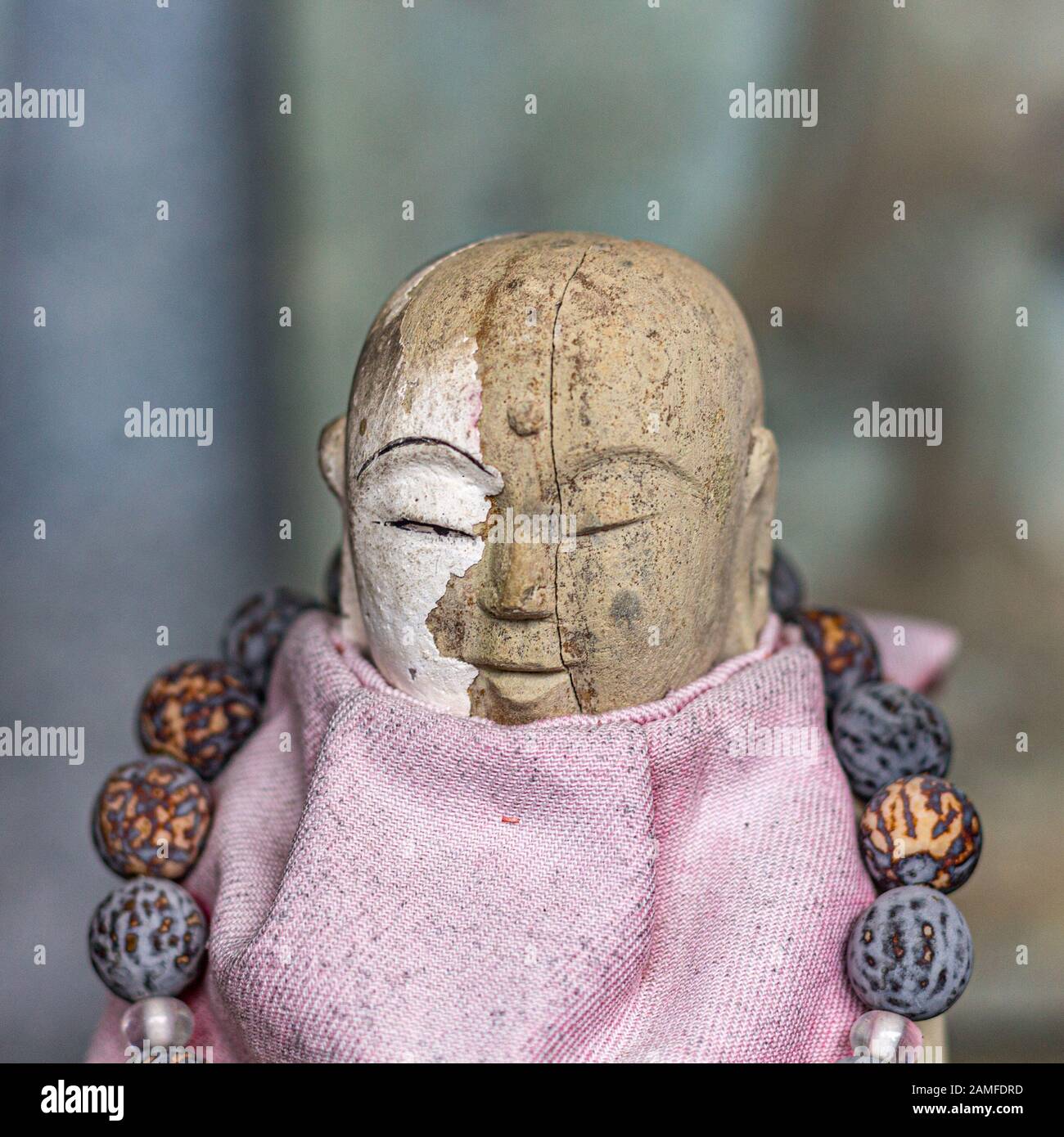 Small weathered ancient stone relic with pink bib and prayer bracelet ...