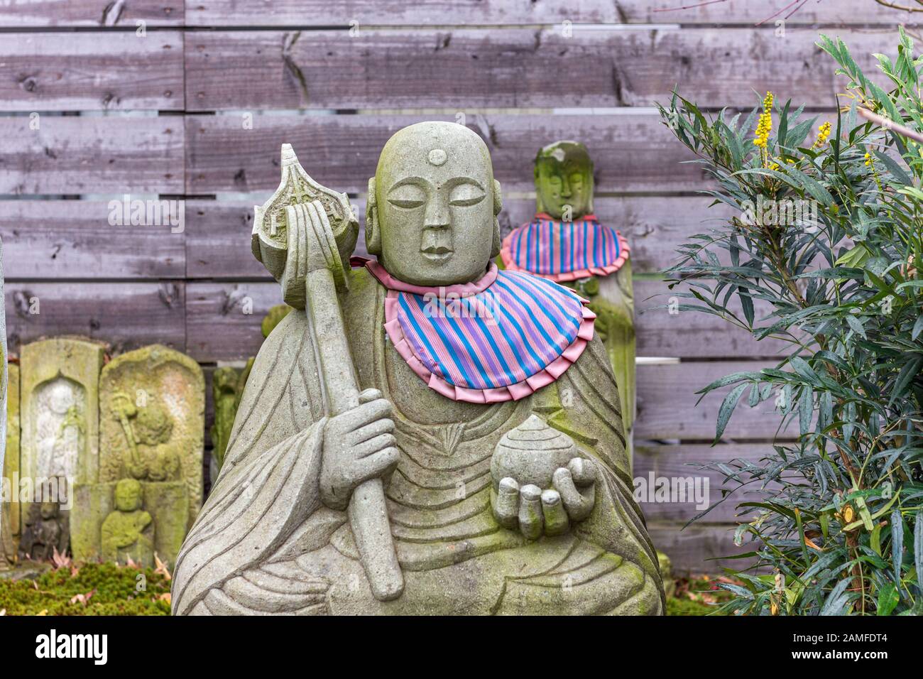 Buddhist stone relic with purple bib and holding symbolic staff and orb ...
