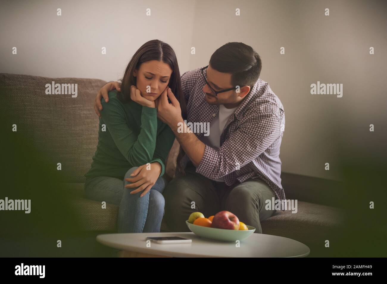 Woman is sad, her man is consoling her Stock Photo - Alamy