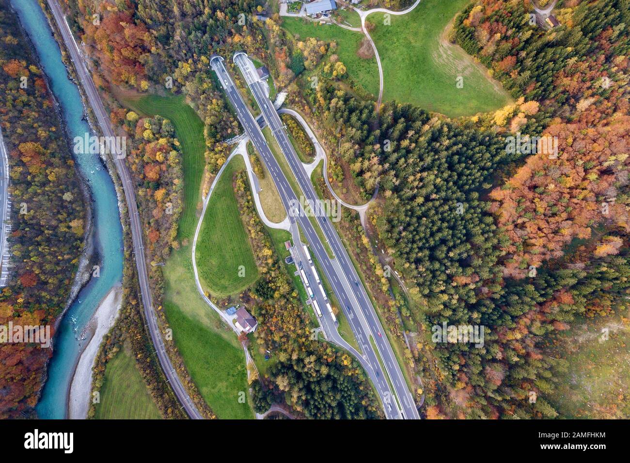 Top dawn aerial view of freeway speed road going out from undeground tunnel between yellow ...