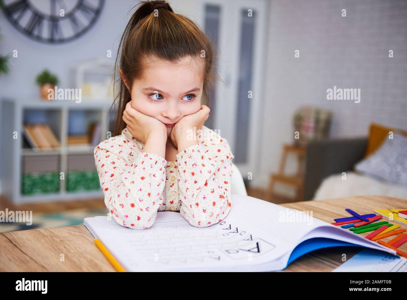 Bored and sad girl doing homework at home Stock Photo - Alamy
