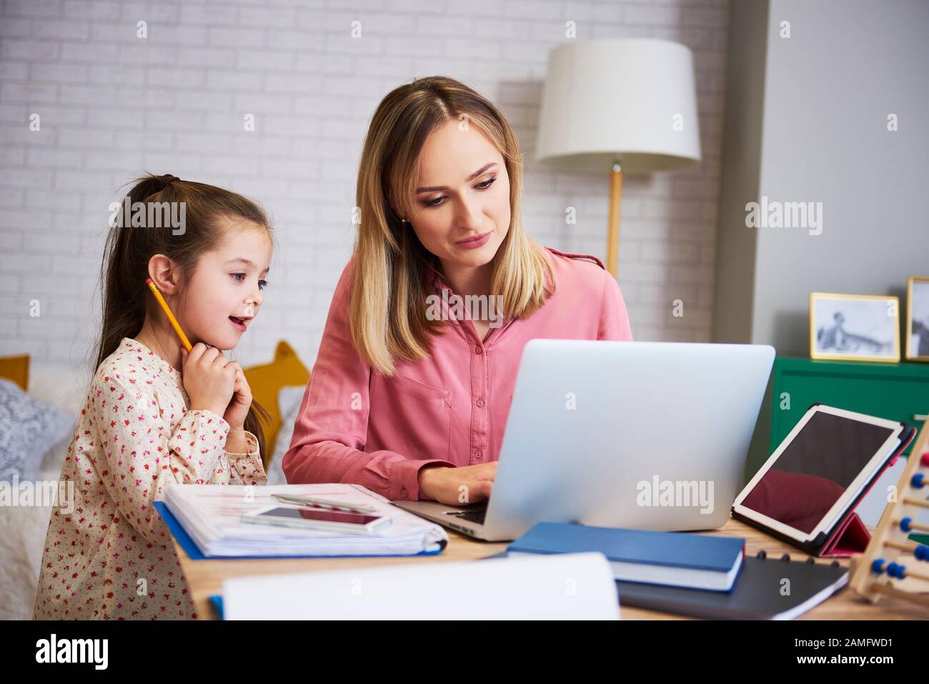Young mother working from home with daughter Stock Photo - Alamy