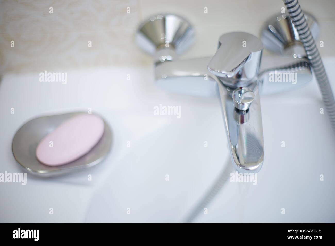 Chrome water tap and pink soap, top view. Shiny faucet in the bathroom ...