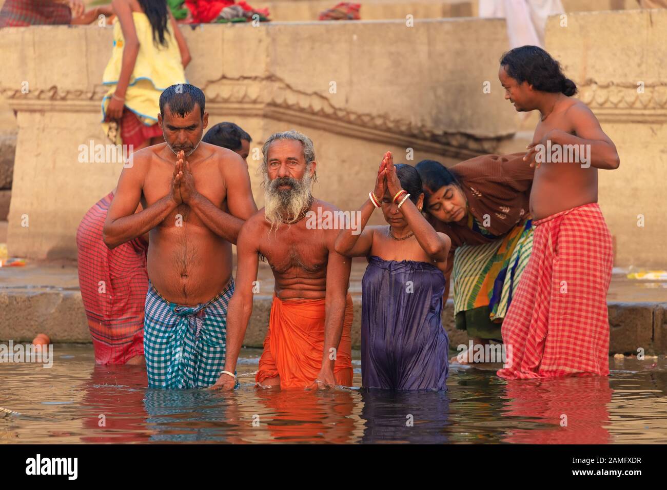 VARANASI, INDIA, JANUARY 18, 2019 : A family is bathing at sunrise ...