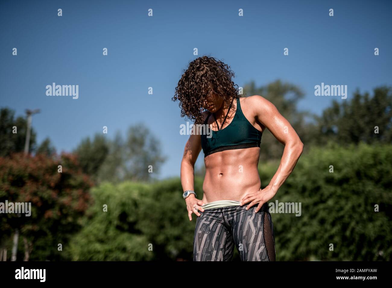 Athletic woman with strong abdominal muscles posing with her hands on ...