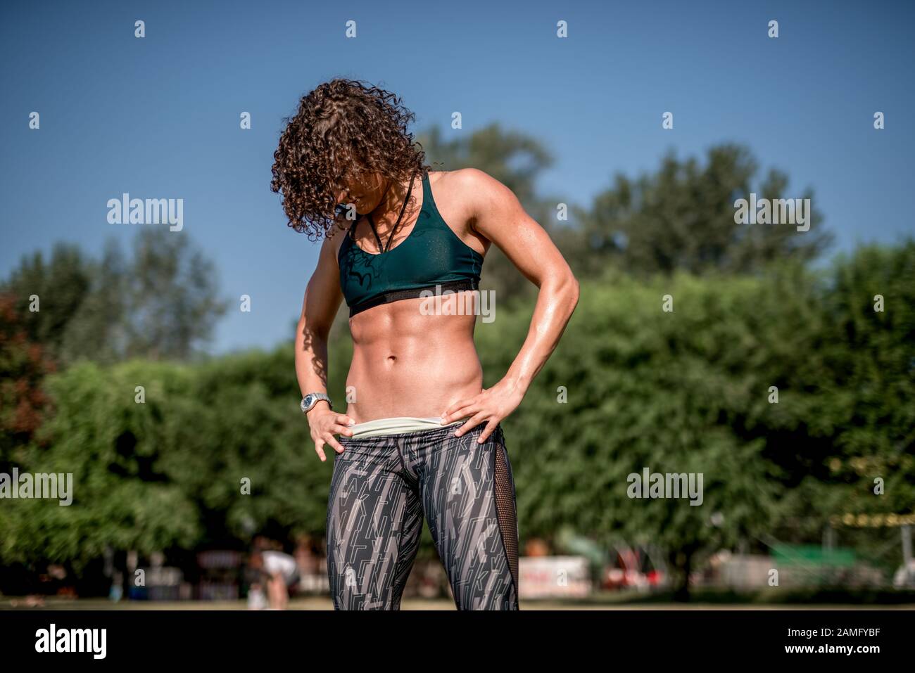 Athletic woman with strong abdominal muscles posing with her hands on ...