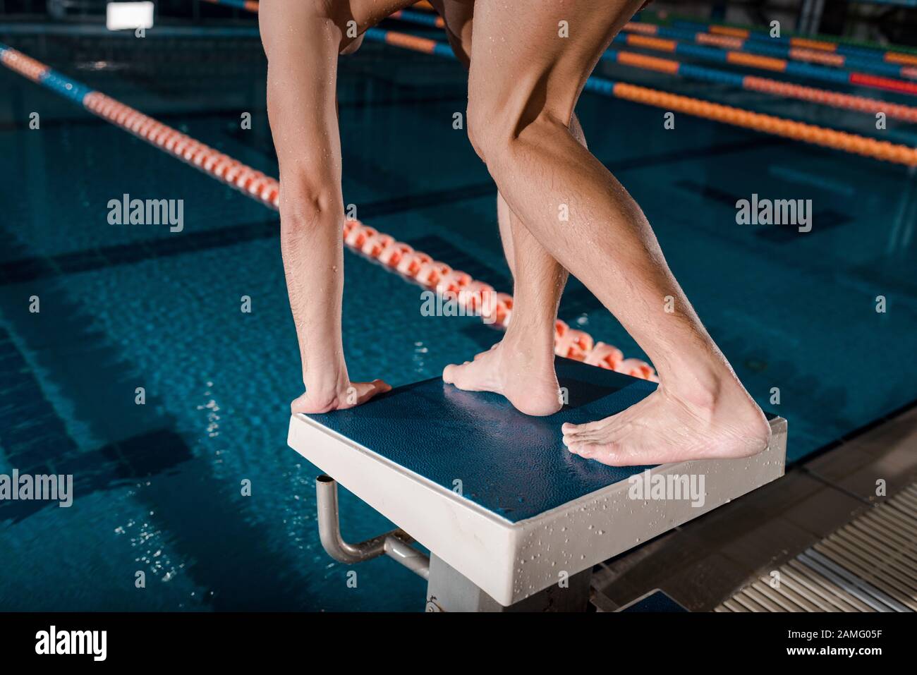 cropped view of man standing in starting pose near swimming pool Stock ...