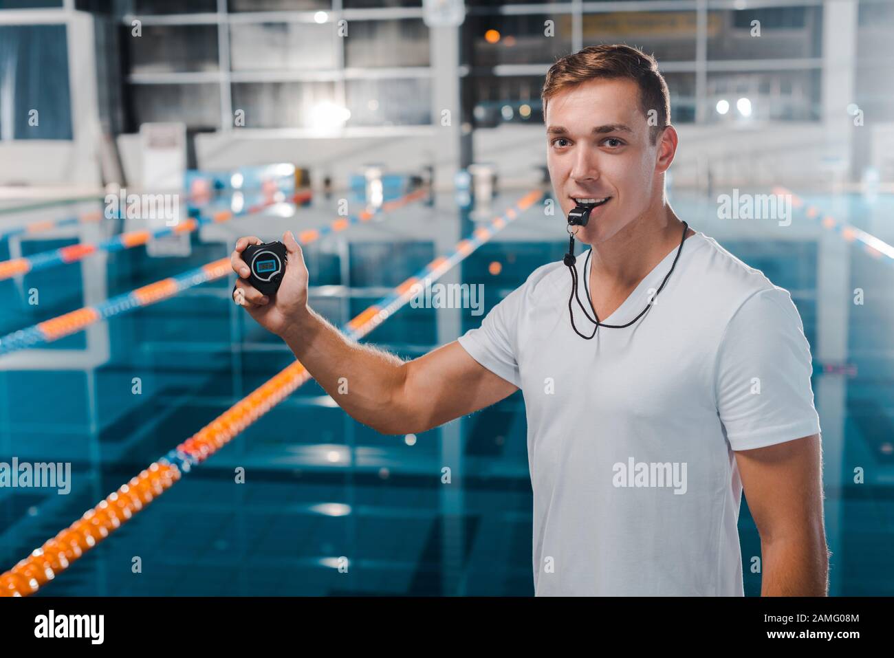 smiling trainer with timer in hand holding whistle in mouth Stock Photo ...