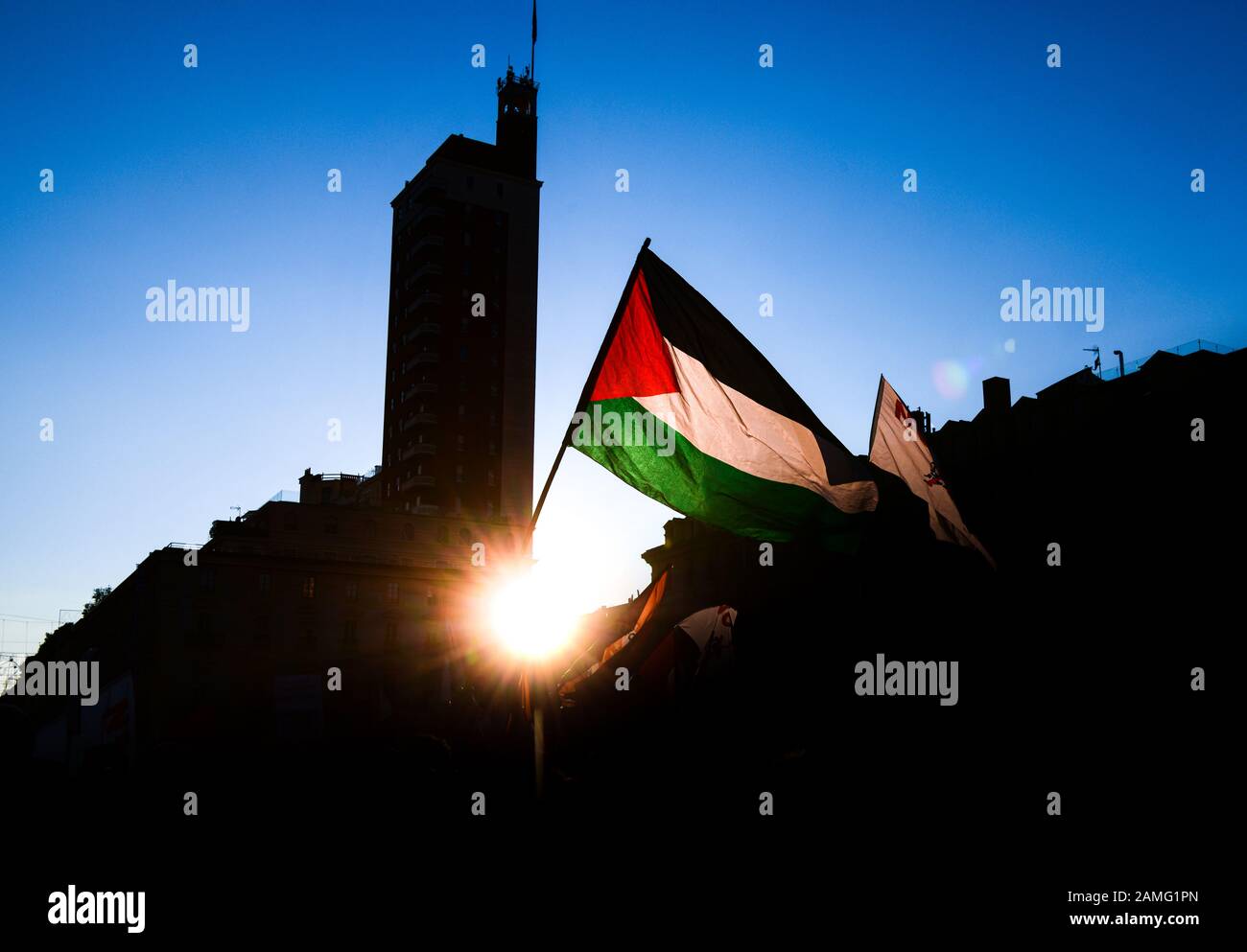 Silhouette of raised Palestinian flag waving against the sun at sunset ...