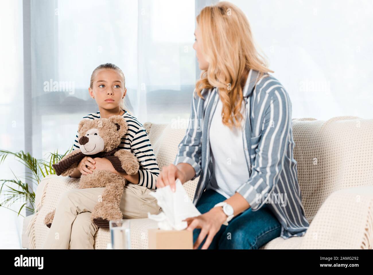 kid with teddy bear looking at sick mother taking tissue at home Stock ...