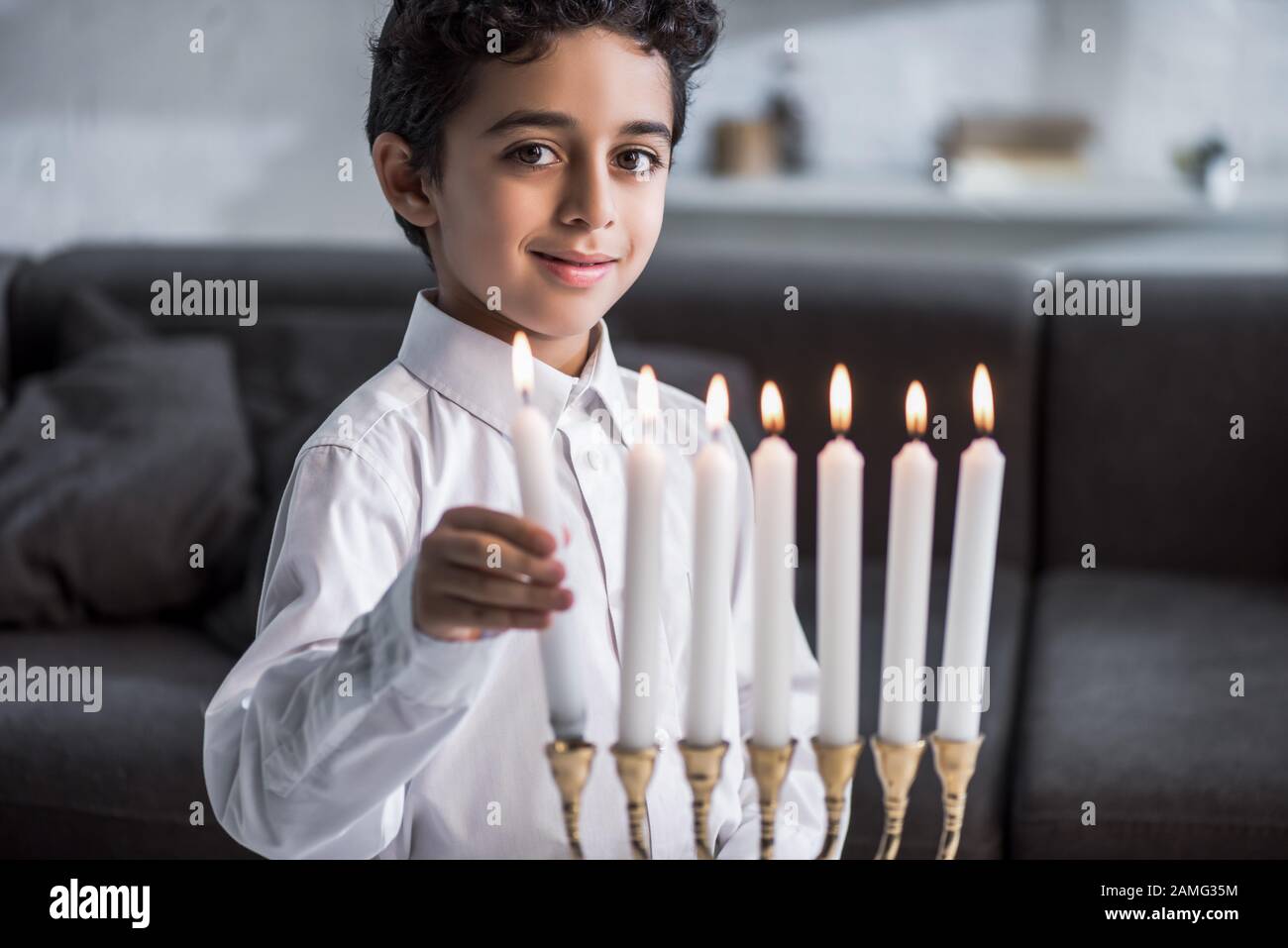 cute and smiling jewish boy in shirt holding candle Stock Photo - Alamy