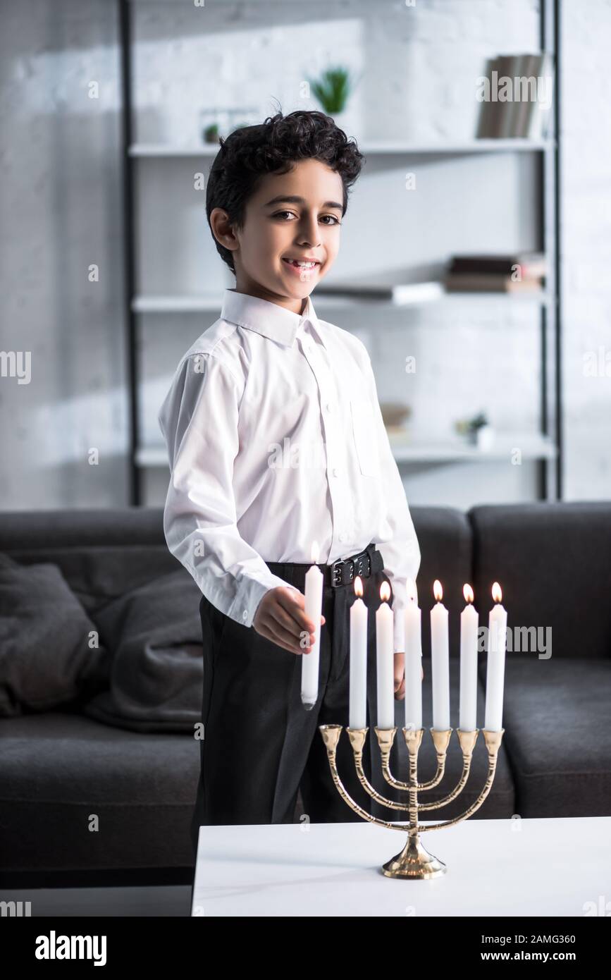 cute and smiling jewish boy in shirt holding candle Stock Photo - Alamy