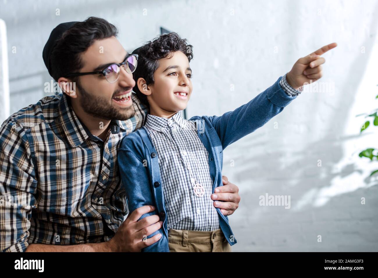 smiling jewish son pointing with finger and looking through window with ...