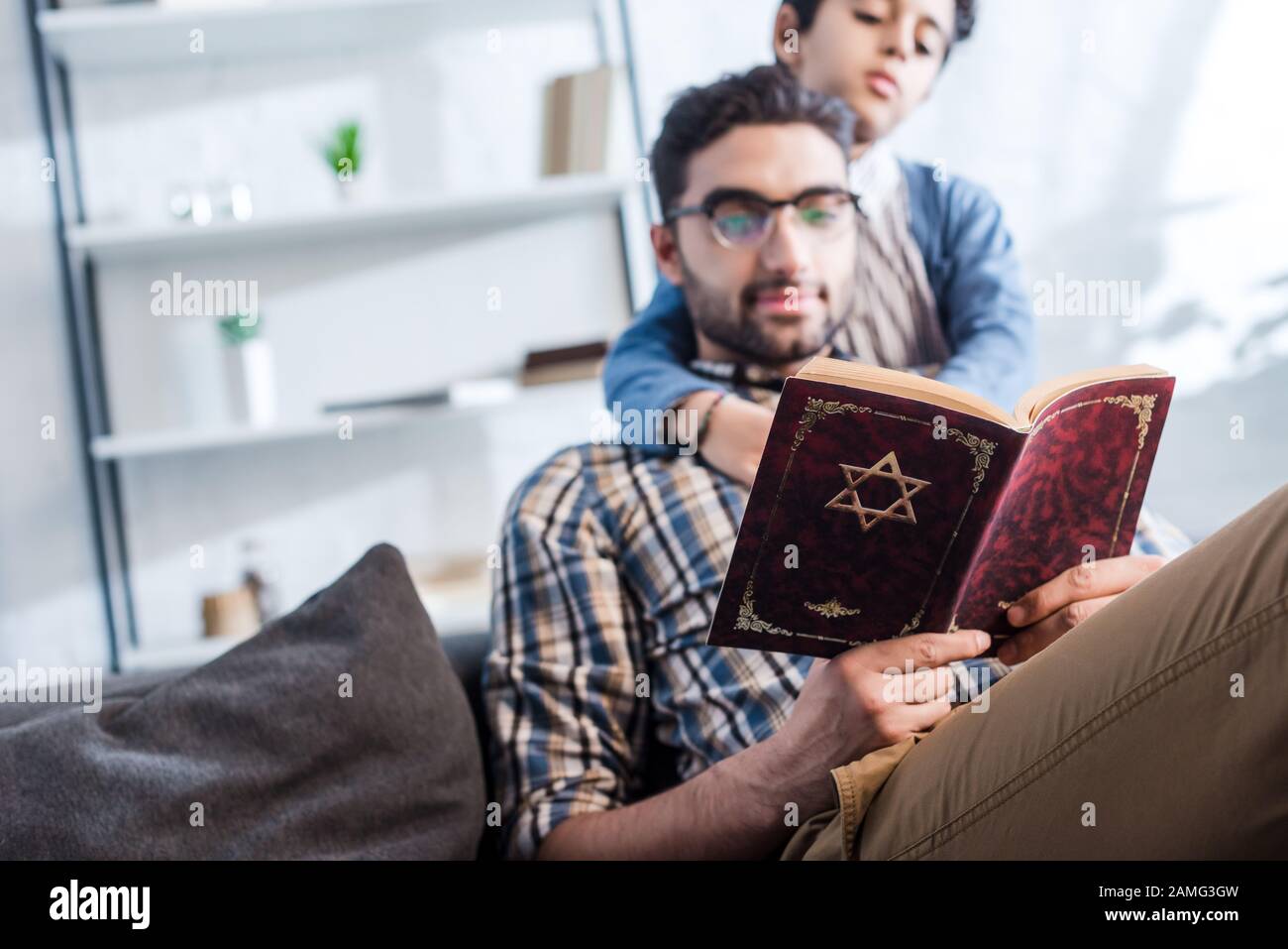 selective focus of jewish father and son reading tanakh in apartment ...