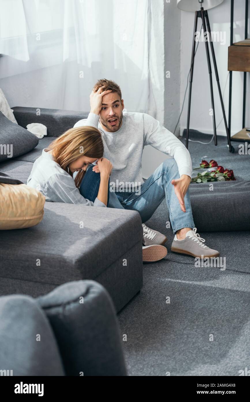 sad woman and shocked man sitting on floor in robbed apartment Stock ...