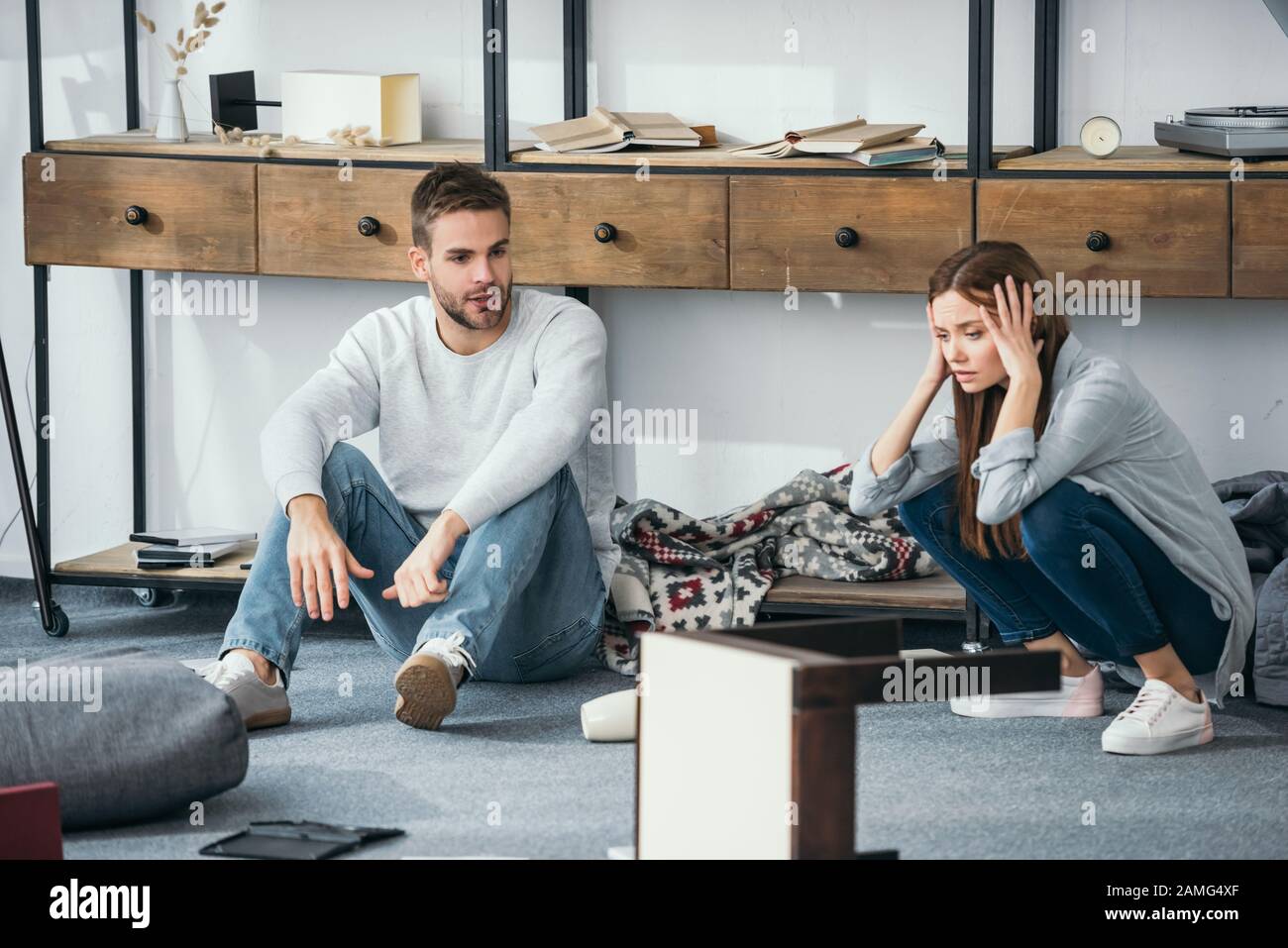 sad woman and handsome man sitting on floor in robbed apartment Stock ...