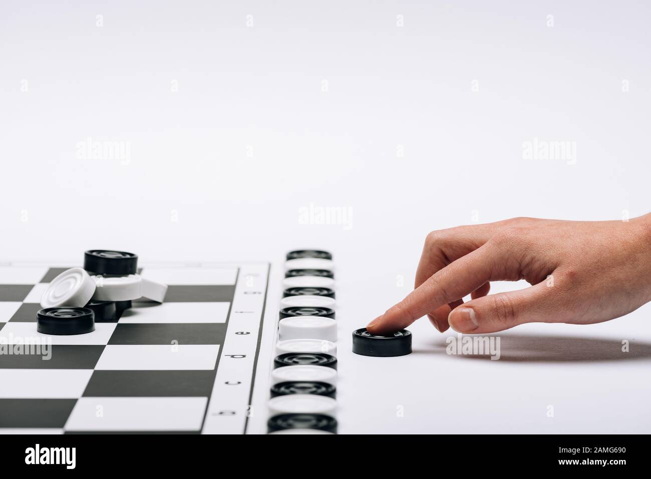 Cropped view of woman holding black checker by checkerboard on white ...