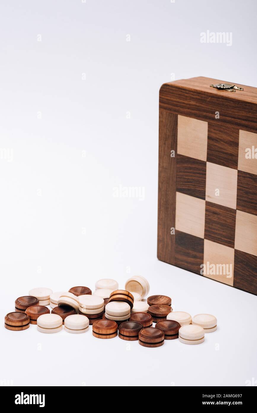 Pile of wooden checkers by checkerboard isolated on white Stock Photo ...