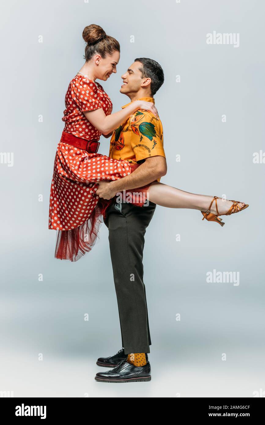 side view of dancer holding cheerful girl while dancing boogie-woogie ...