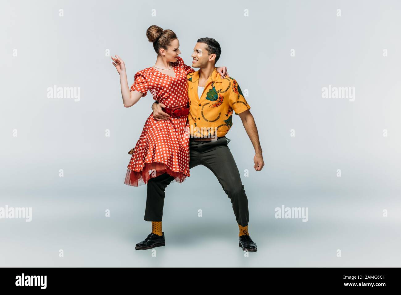 young dancer holding partner while dancing boogie-woogie on grey ...
