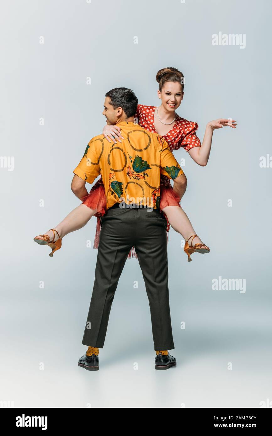 back view of young dancer holding pretty girl while dancing boogie ...