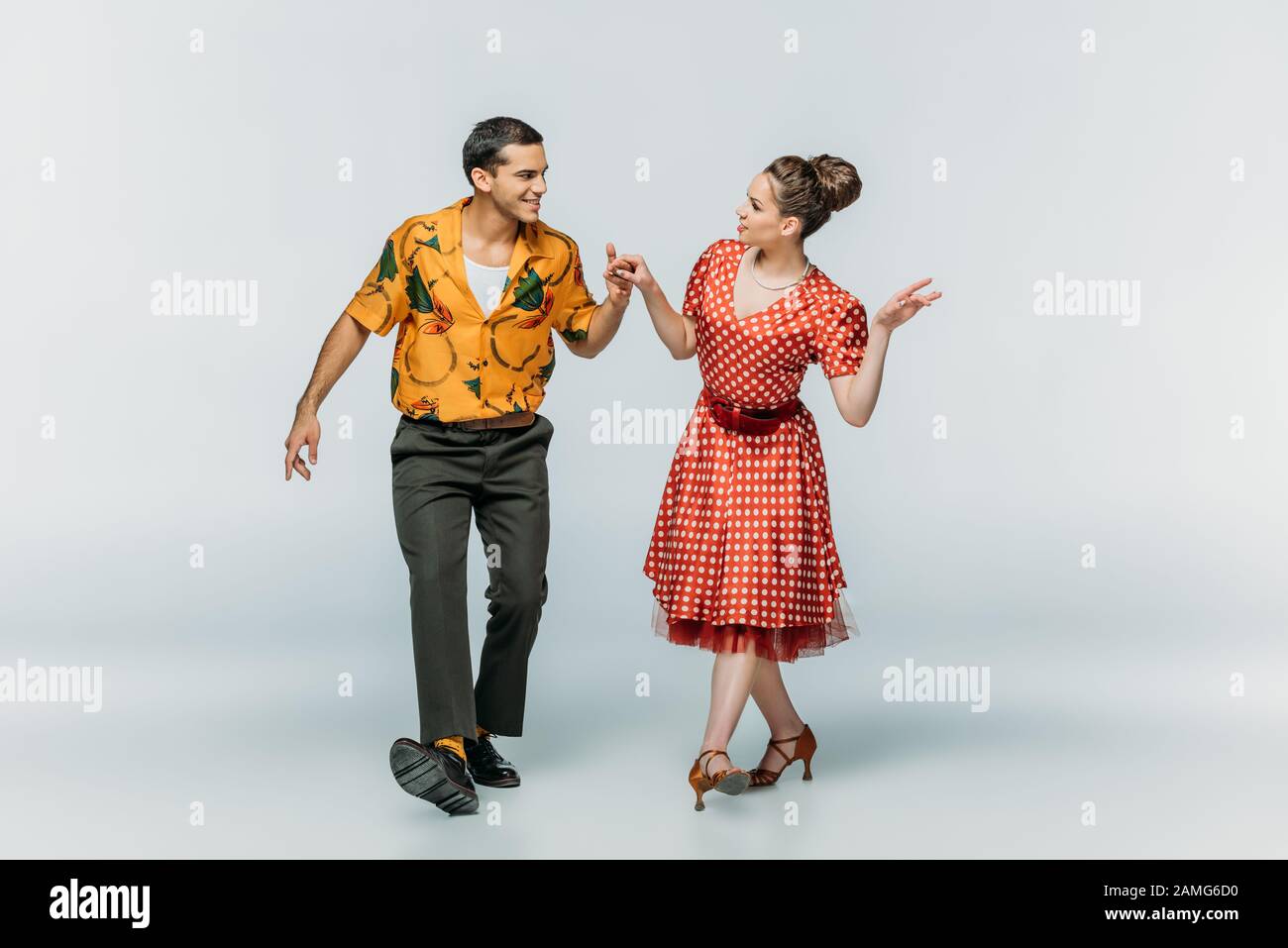 young dancers looking at each other while dancing boogie-woogie on grey ...