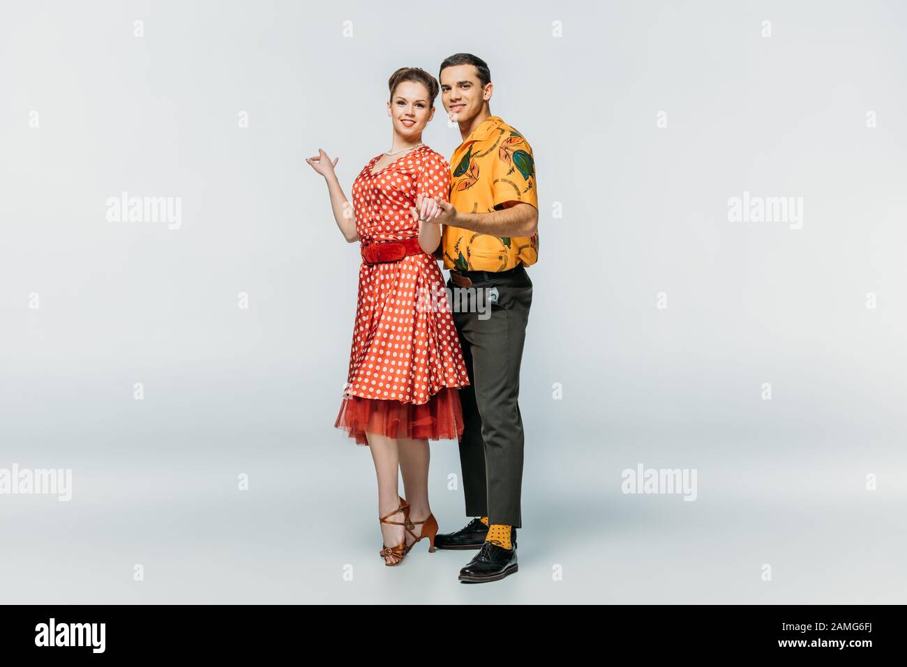 happy dancers holding hands while dancing boogie-woogie on grey ...