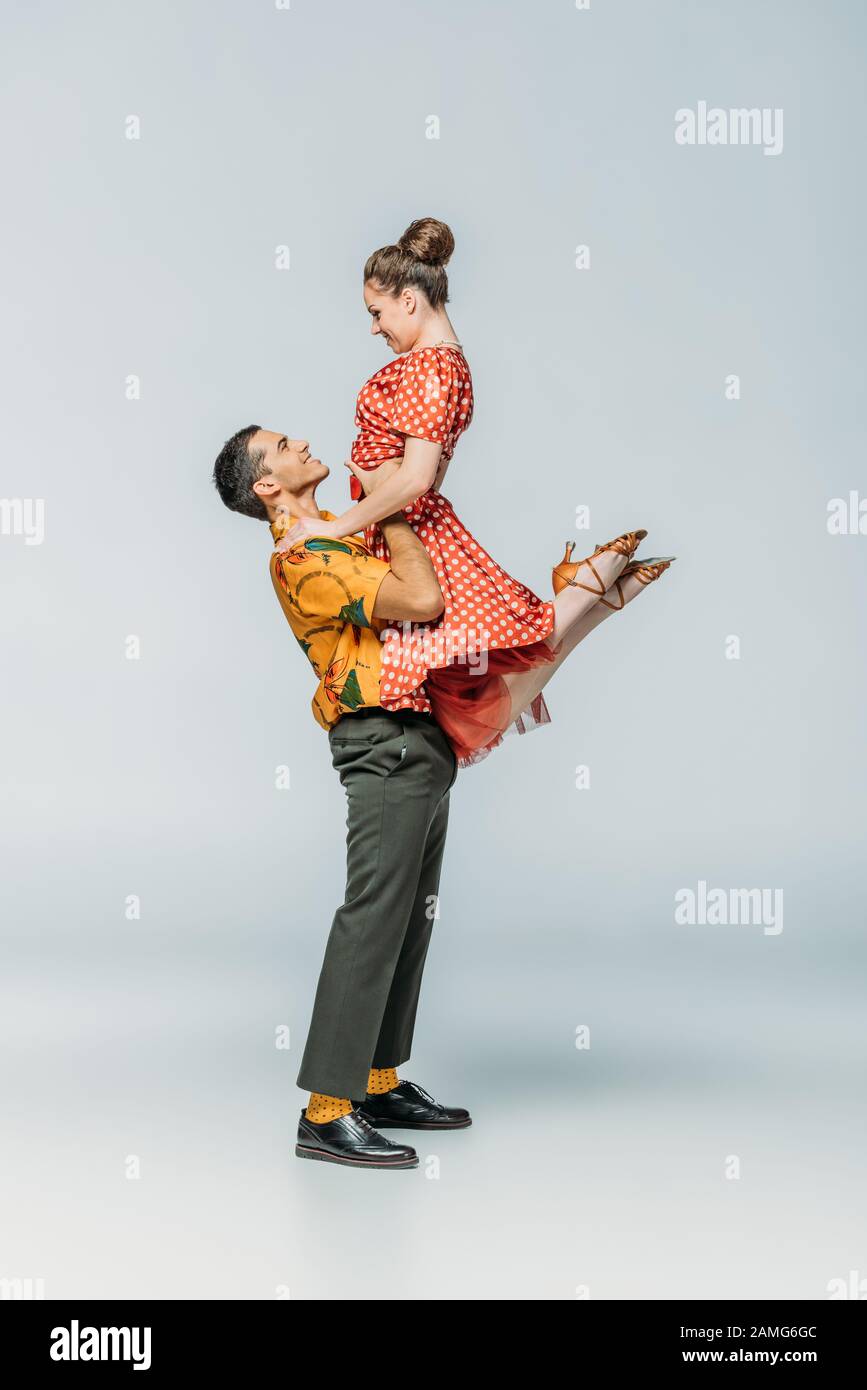 side view of handsome dancer holding partner while dancing boogie ...