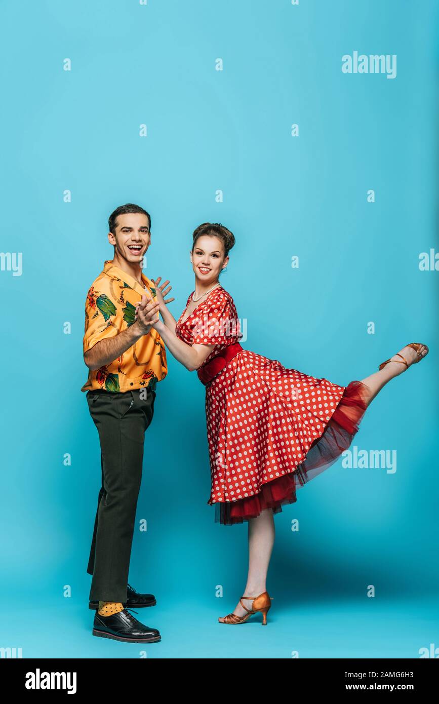 happy dancers looking at camera while dancing boogie-woogie on blue ...