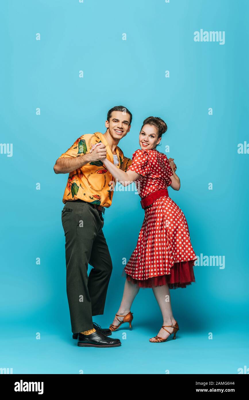 stylish dancers holding hands while dancing boogie-woogie on blue ...