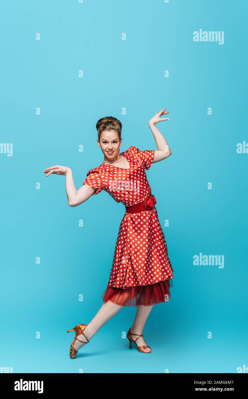 beautiful dancer looking at camera while dancing boogie-woogie on blue ...