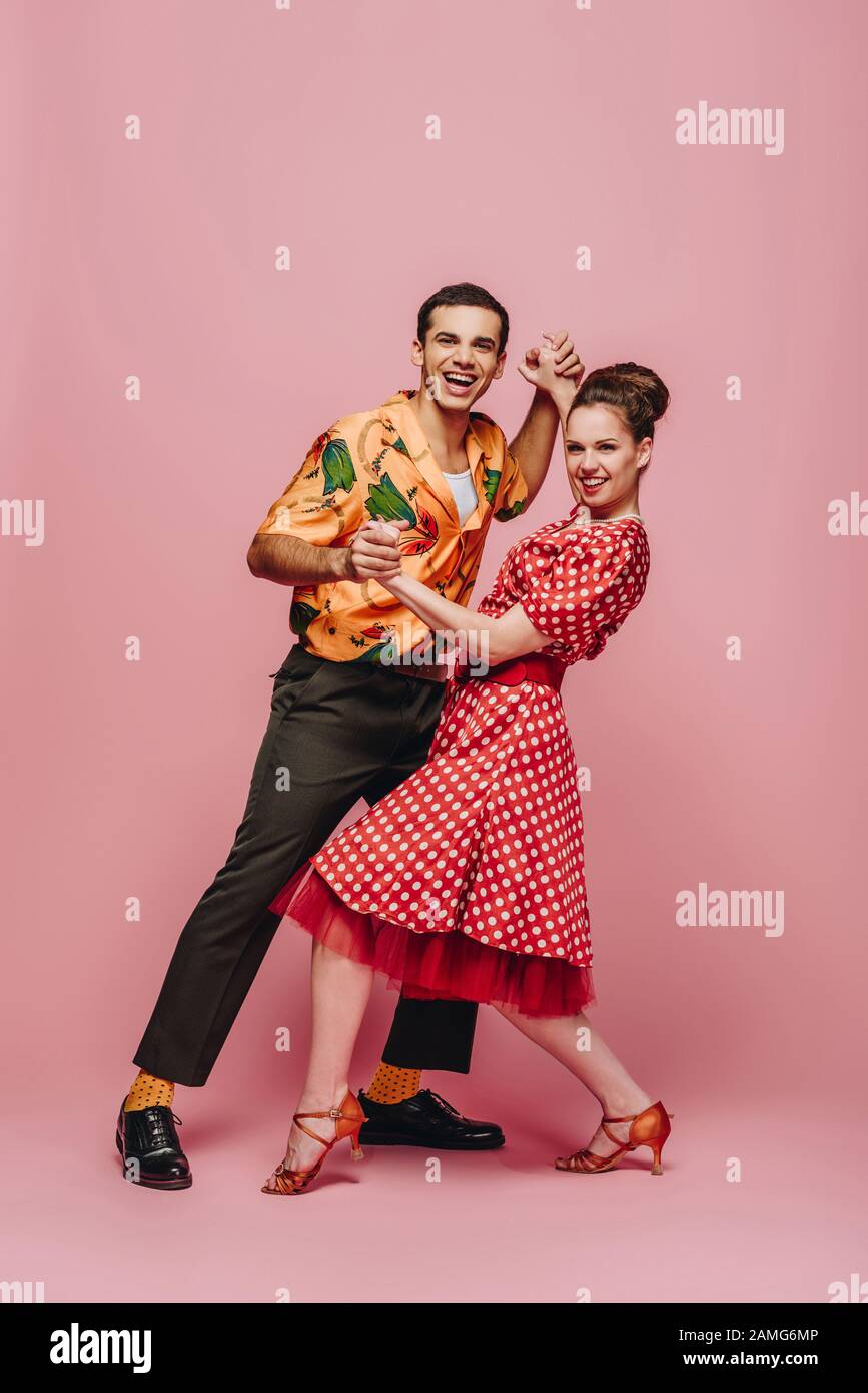 elegant dancers holding hands while dancing boogie-woogie on pink ...