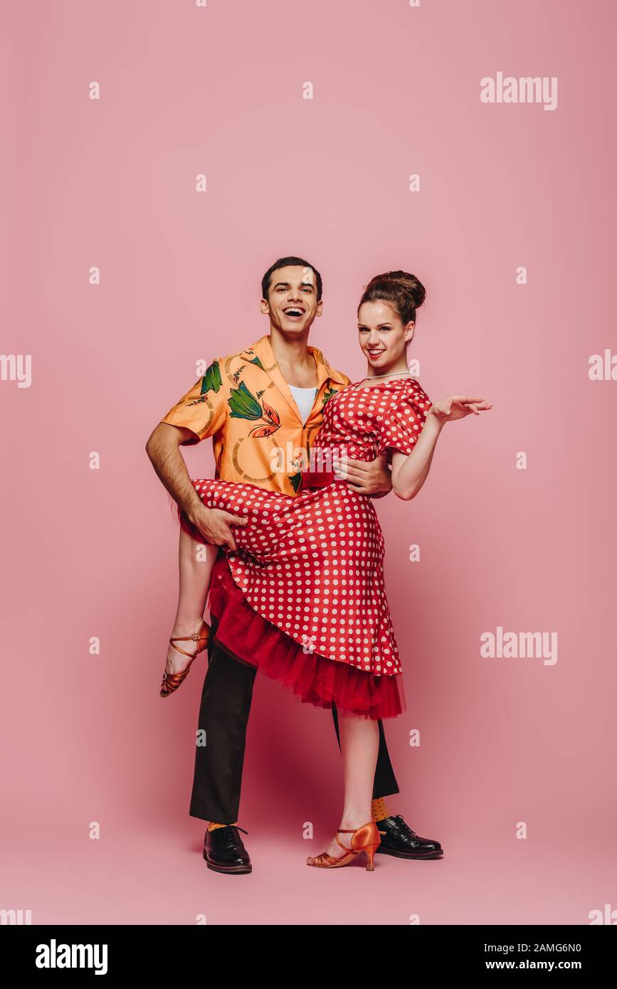 smiling dancer hugging partner while dancing boogie-woogie on pink ...