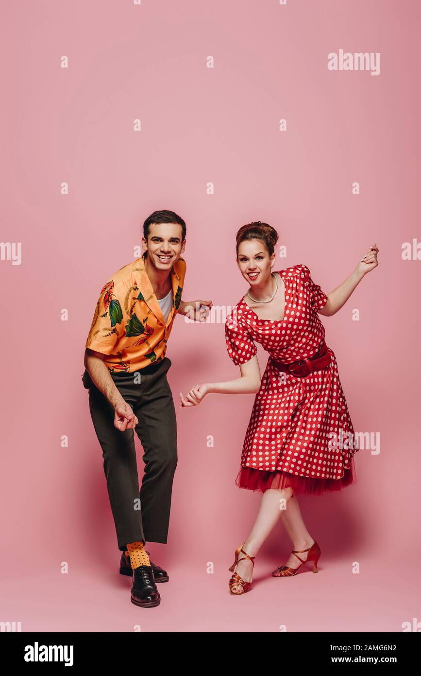 young dancers looking at camera while dancing boogie-woogie on pink ...