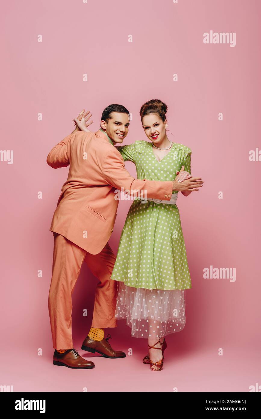 stylish dancers holding hands while dancing boogie-woogie on pink ...
