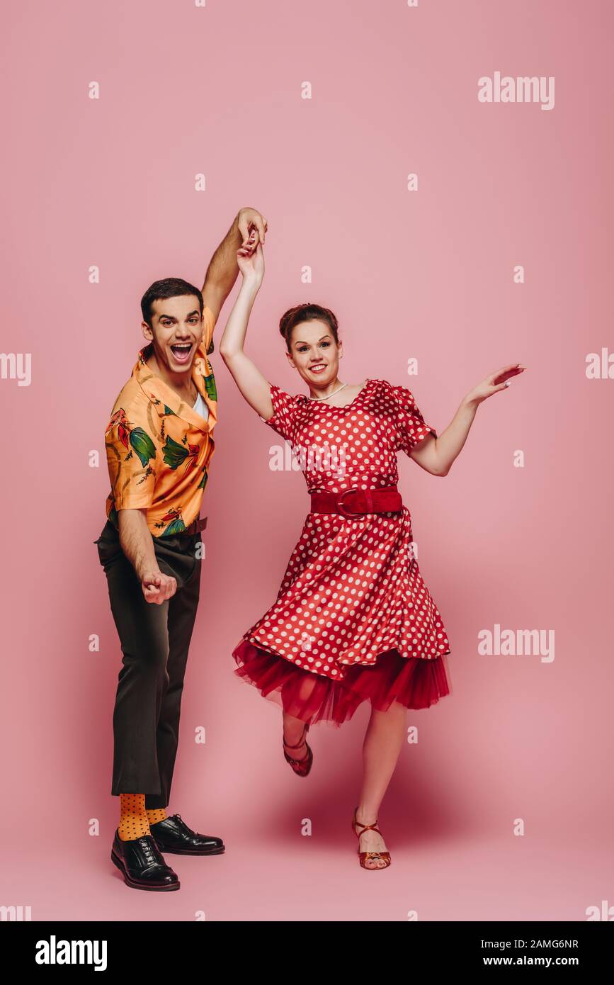 cheerful dancers holding hands while dancing boogie-woogie on pink ...