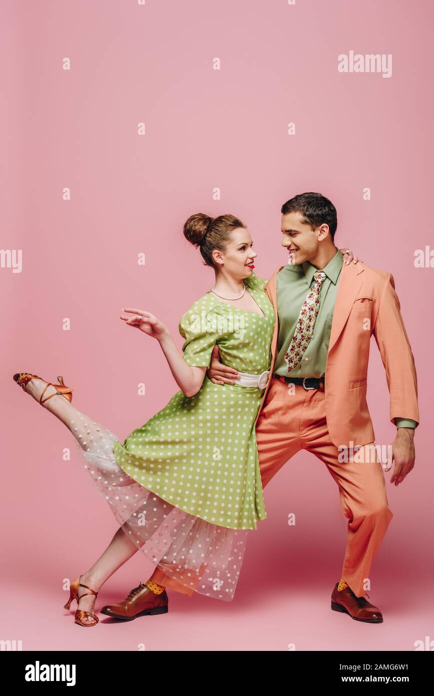 handsome dancer hugging girl while dancing boogie-woogie on pink ...