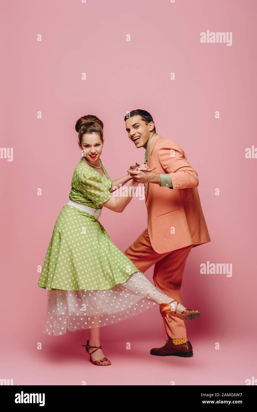 elegant dancers holding hands while dancing boogie-woogie on pink ...