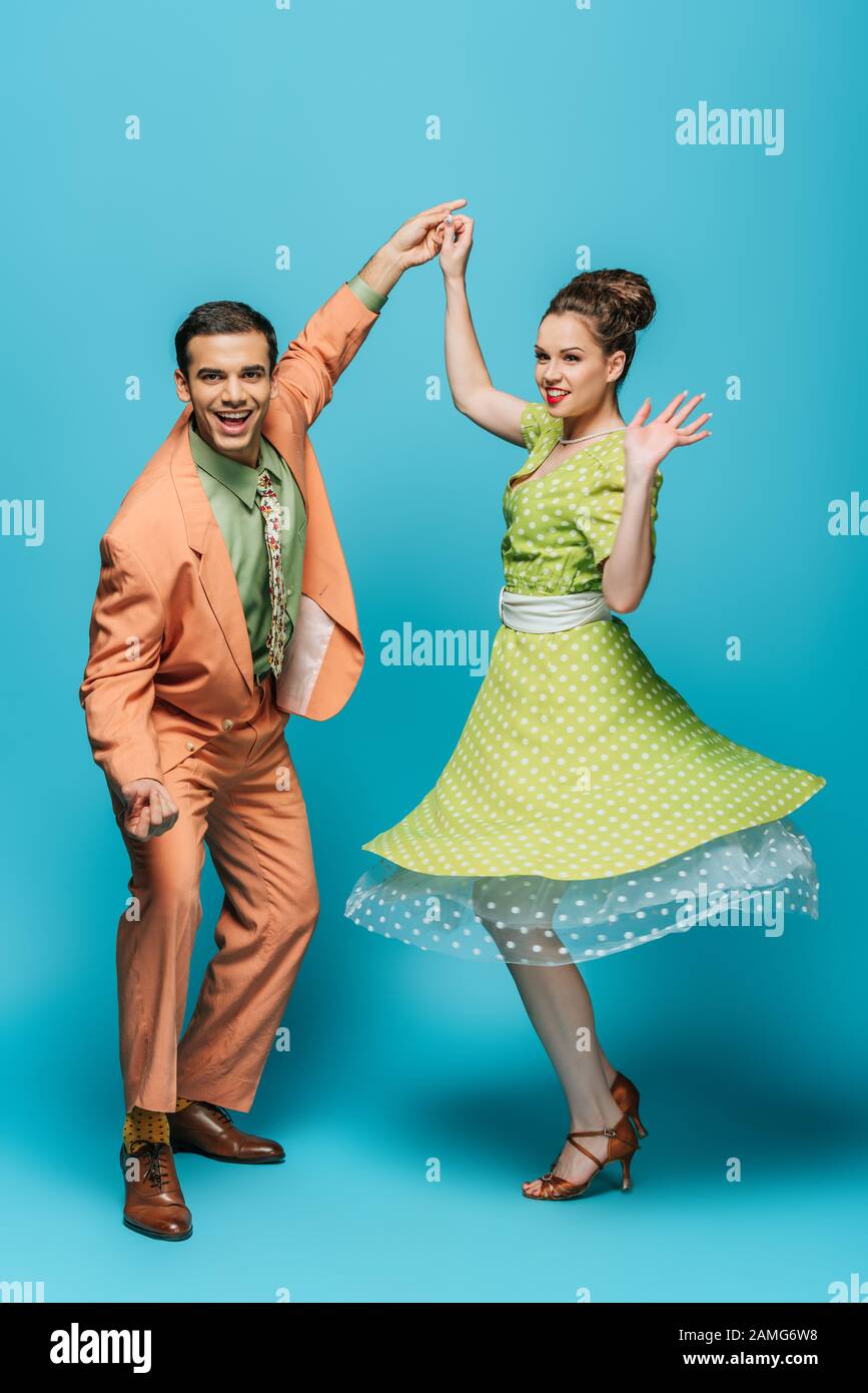 stylish dancers holding hands while dancing boogie-woogie on blue ...